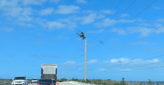 Linesman Balancing on Helicopter for Work - Sharedots